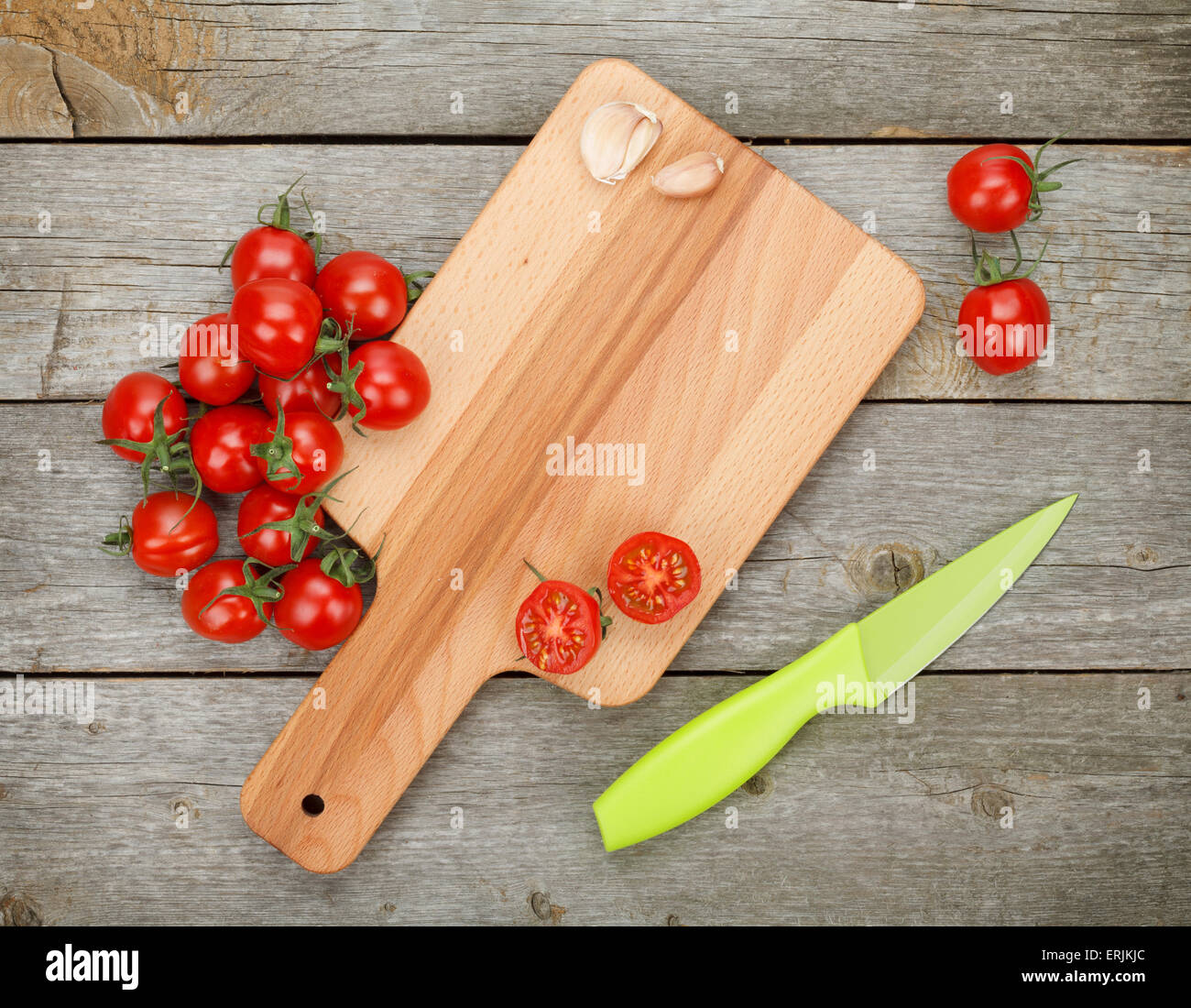 Cherry tomatoes with knife on cutting board over wooden table ...