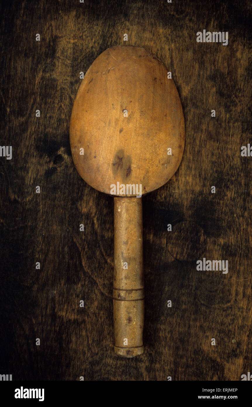 Much used wooden spoon with wide shallow bowl and short handle lying ...