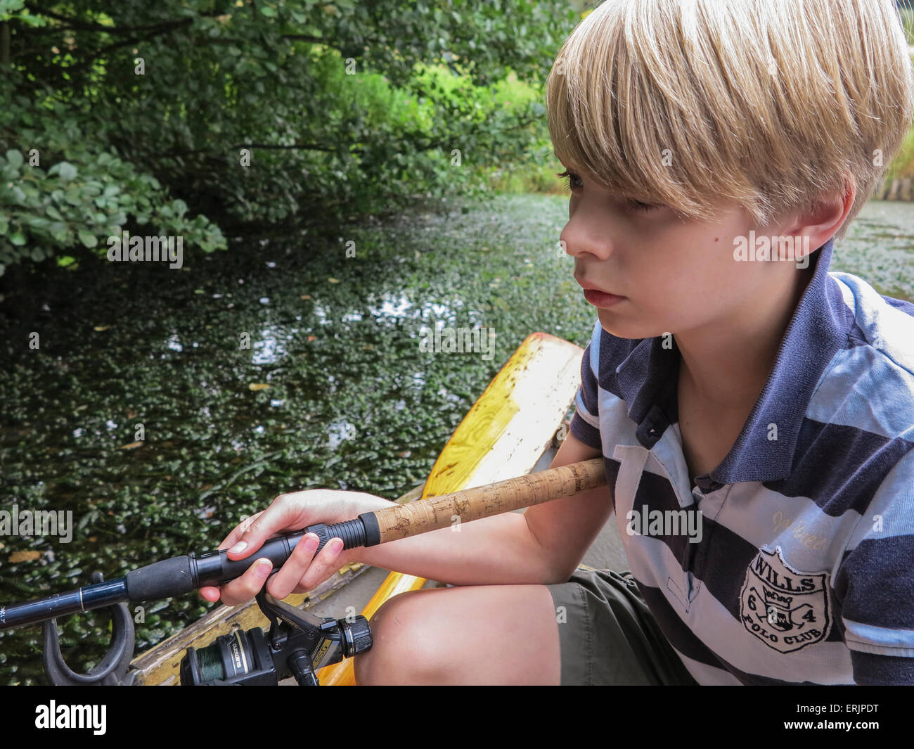 A young boy fishes from a boat in a lake Stock Photo - Alamy