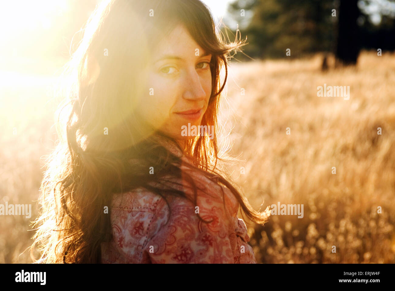 A backlit, young woman smiles and poses for a portrait in a large ...