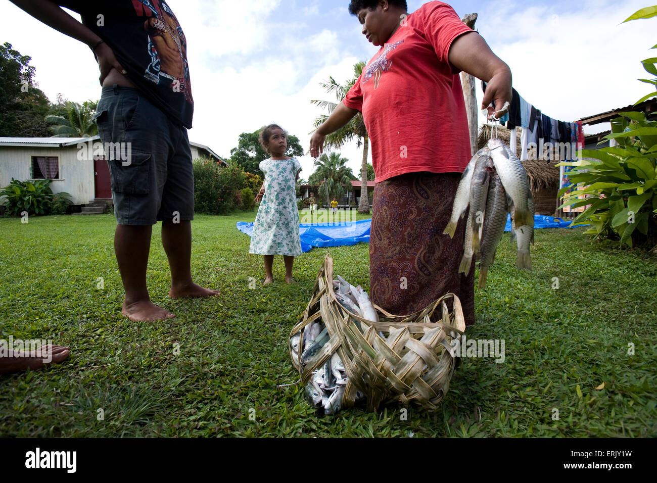 A mother holds up a string of fish comparing the catch and wondering ...