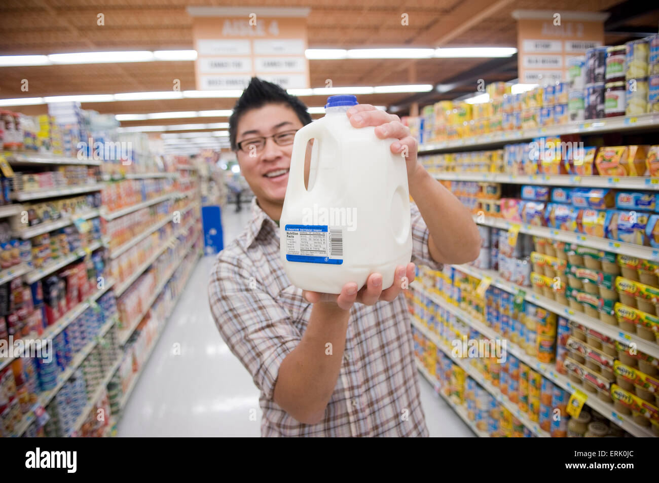 Young adult Asian male smiles while holding a gallon of milk out while ...
