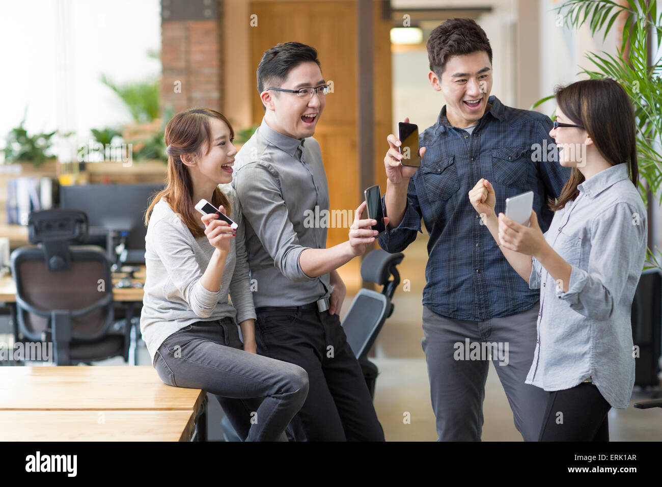 IT workers celebrating with smart phones in office Stock Photo - Alamy