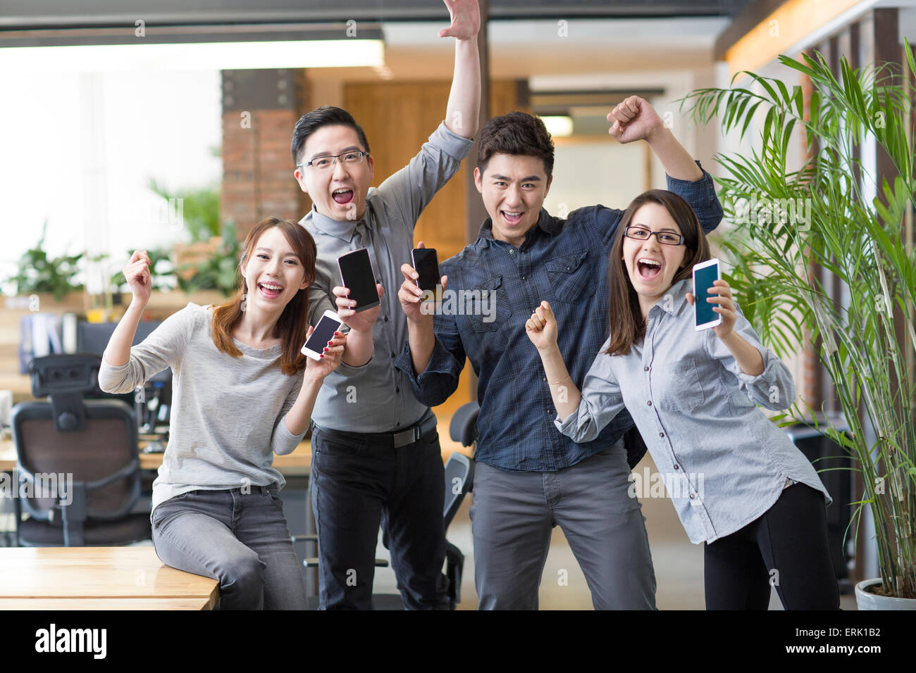 IT workers celebrating with smart phones in office Stock Photo - Alamy