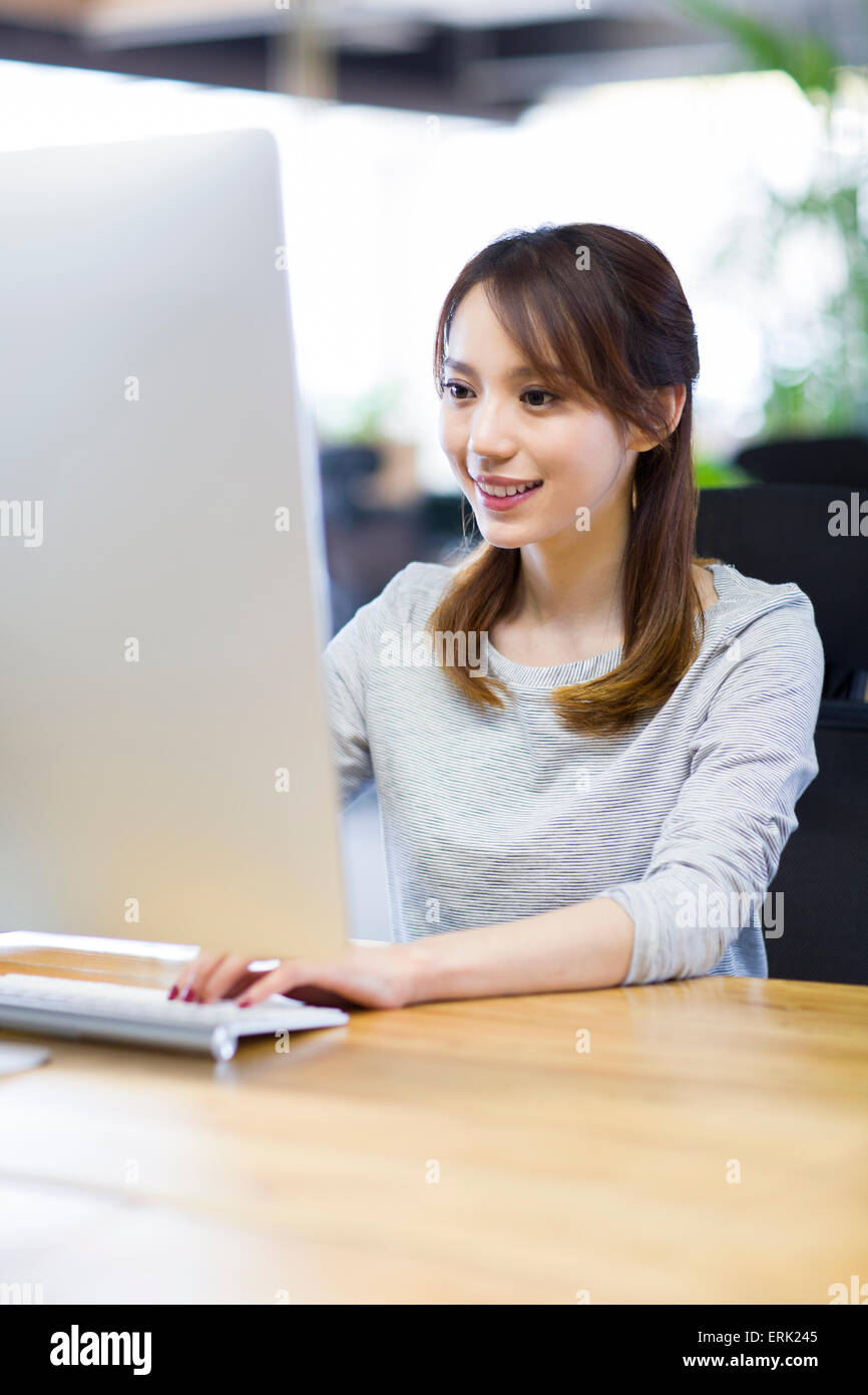 Young woman using computer in office Stock Photo - Alamy