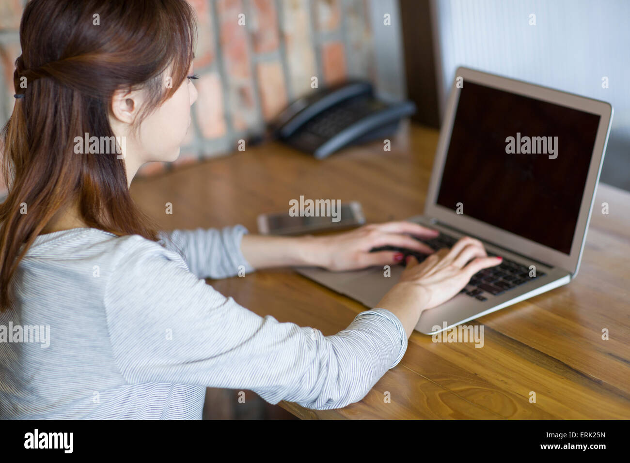 Young woman using laptop in office Stock Photo - Alamy