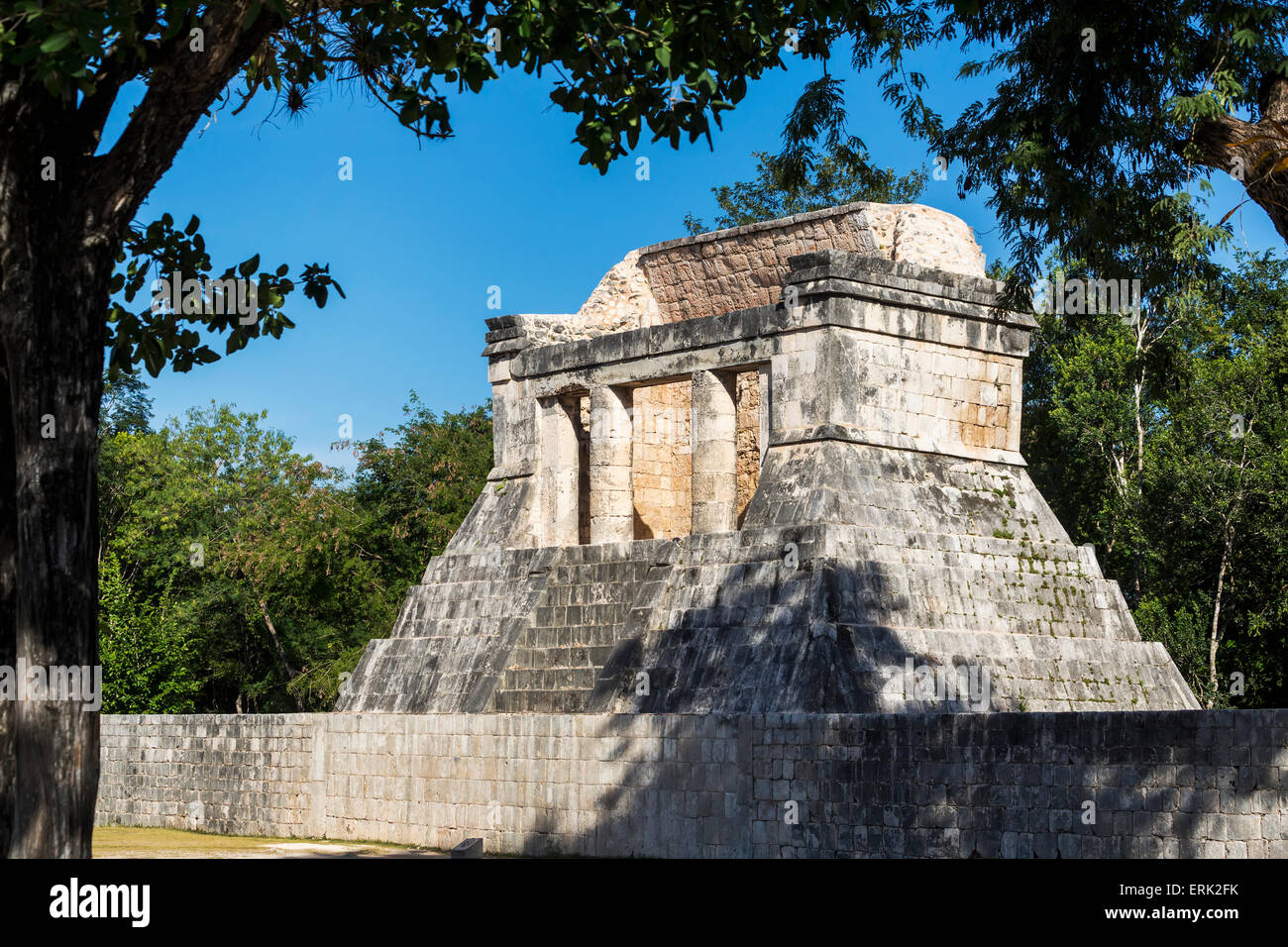 Ancient Mayan Temple with round columns framed by trees and blue sky ...