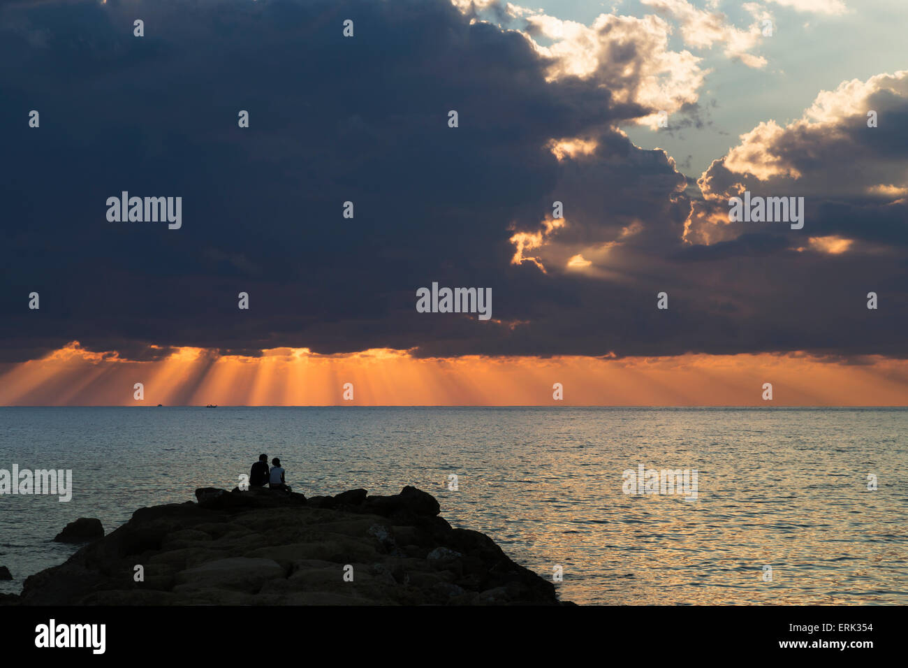 Dramatic sky with orange sun rays reaching down to the water on the ...