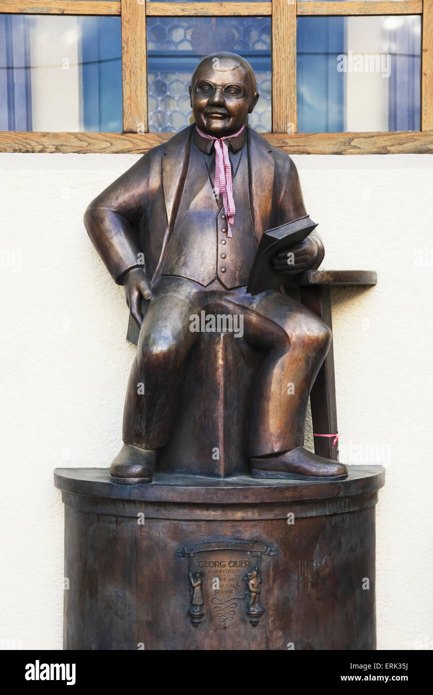 Bronze statue of a man sitting and holding a book; Bayern, Germany ...