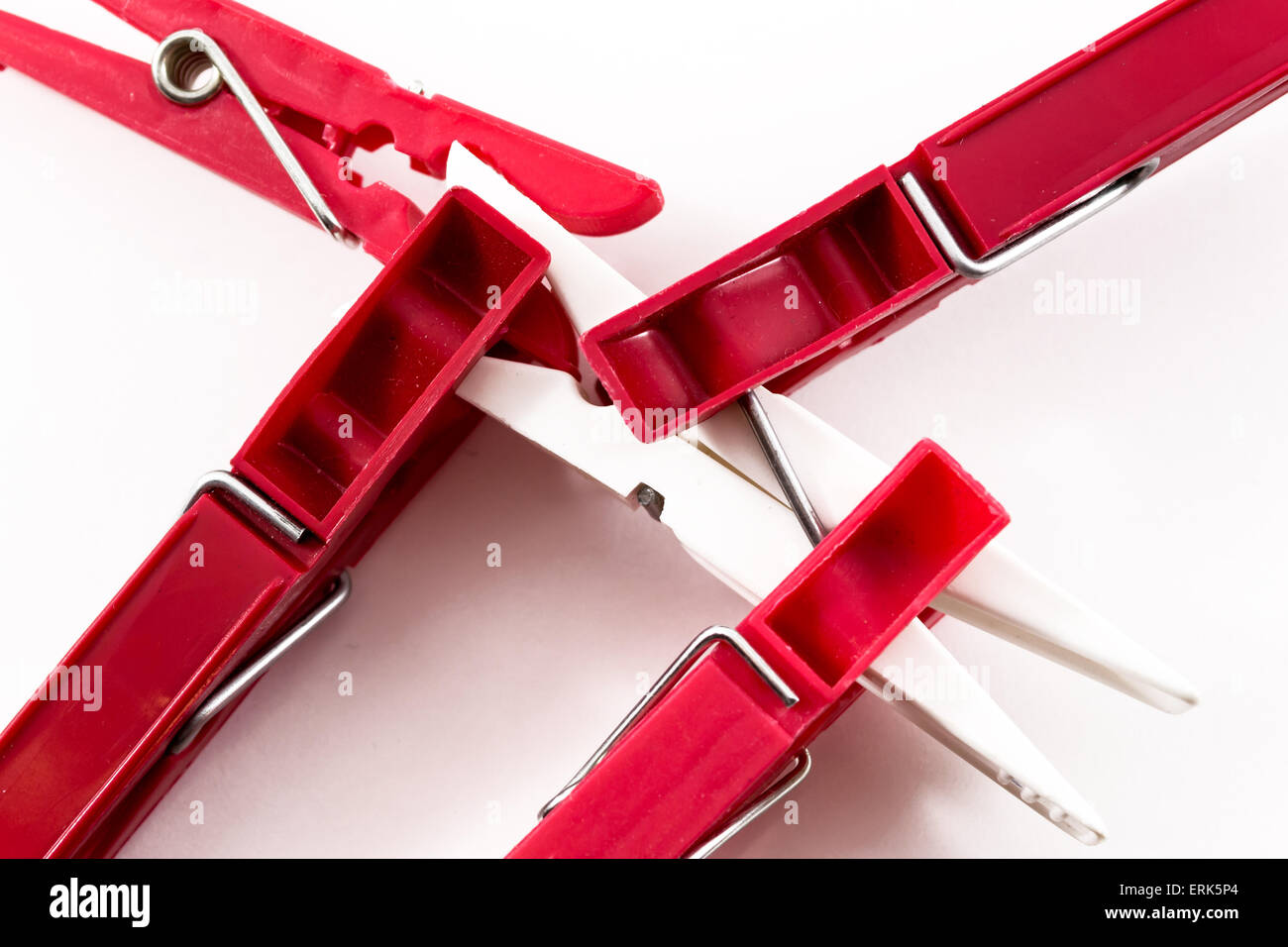 Four dark red plastic pegs overcoming a single solitary white plastic ...