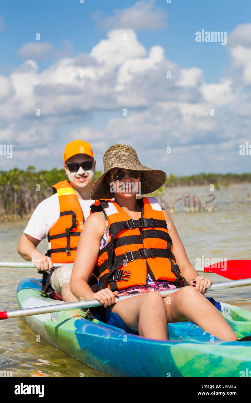 Couple in double kayakers floating in magrove lagoon with blue sky and ...