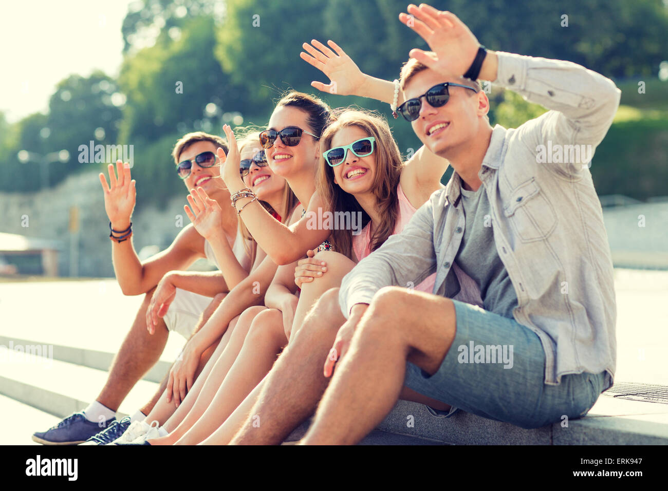 group of smiling friends sitting on city street Stock Photo - Alamy