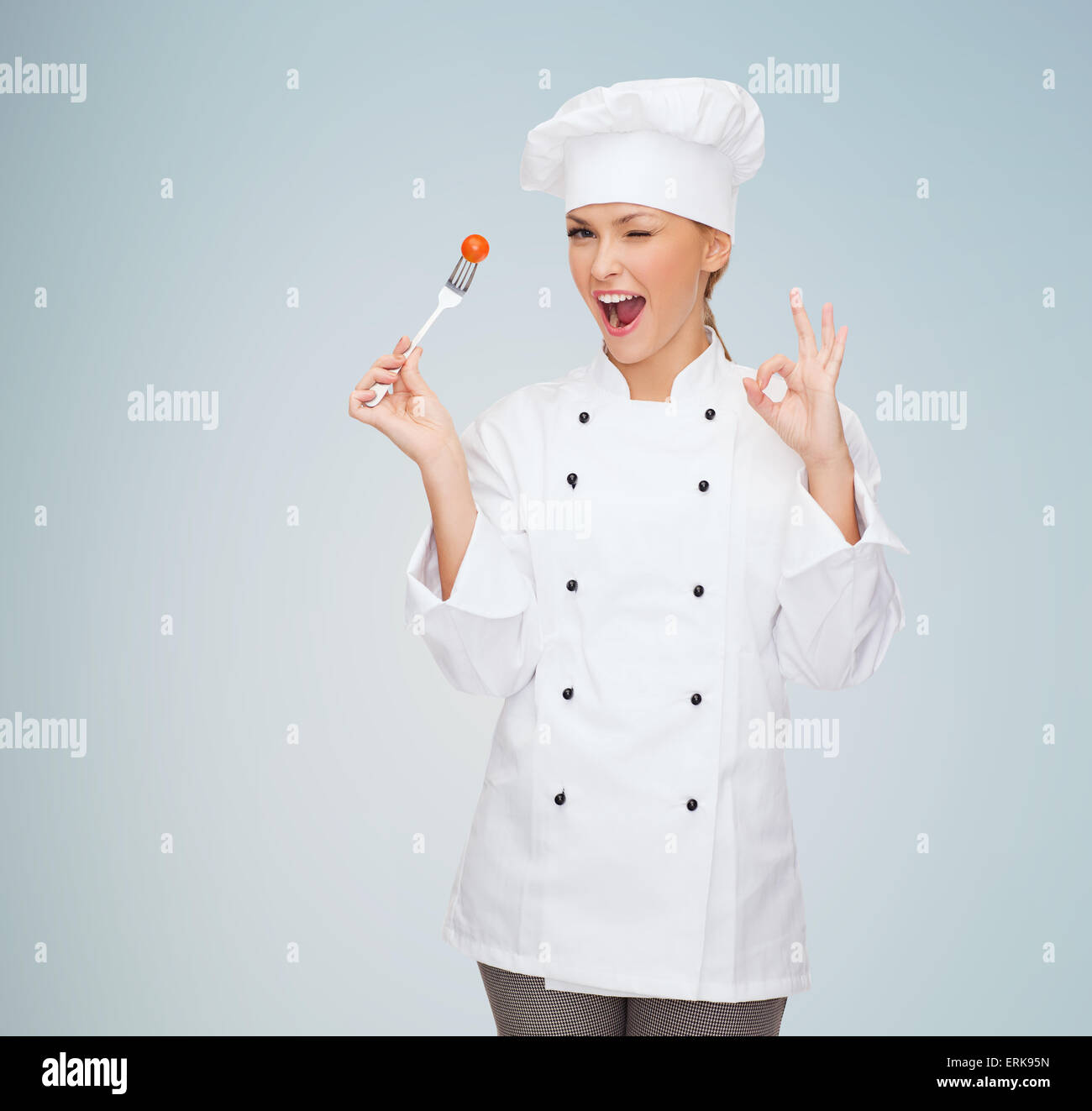 smiling female chef with fork and tomato Stock Photo - Alamy