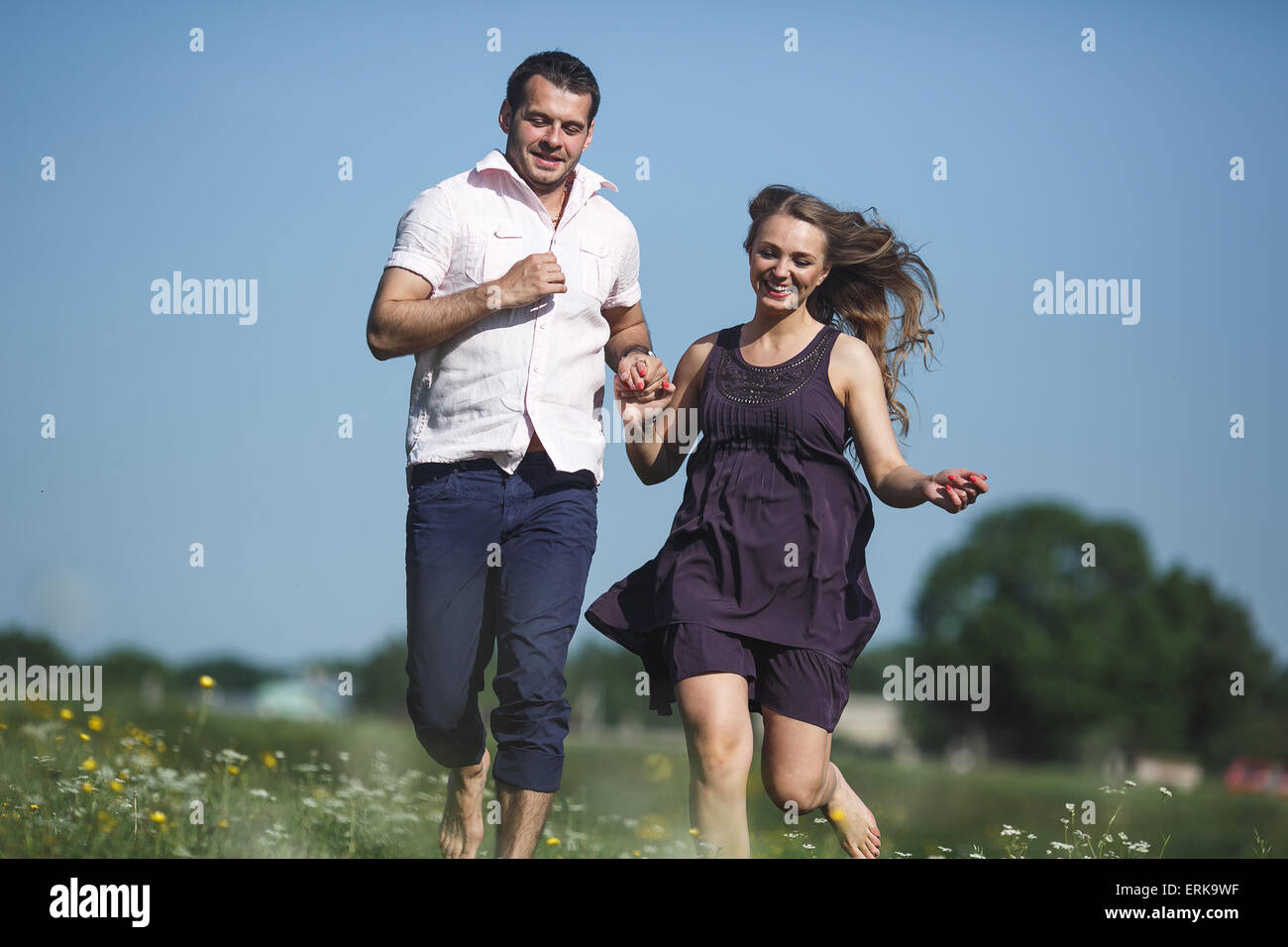 Couple running in field and have fun Stock Photo - Alamy