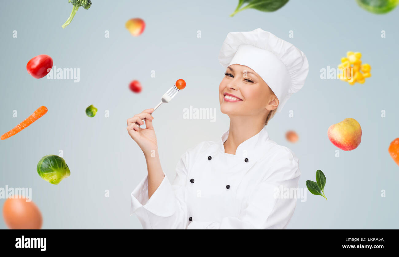 smiling female chef with fork and tomato Stock Photo - Alamy