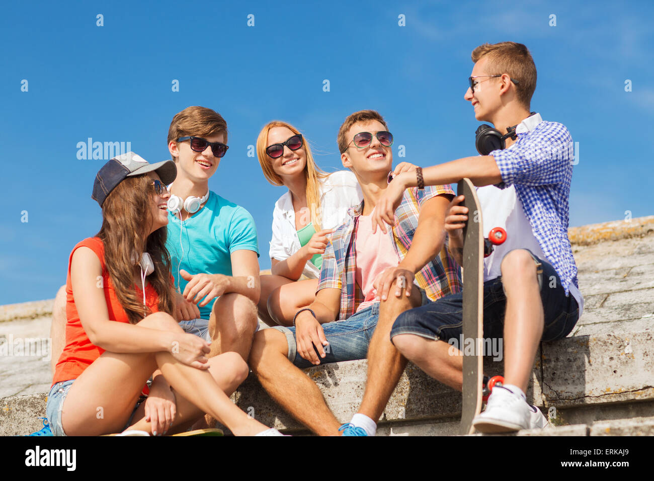 group of smiling friends sitting on city street Stock Photo - Alamy