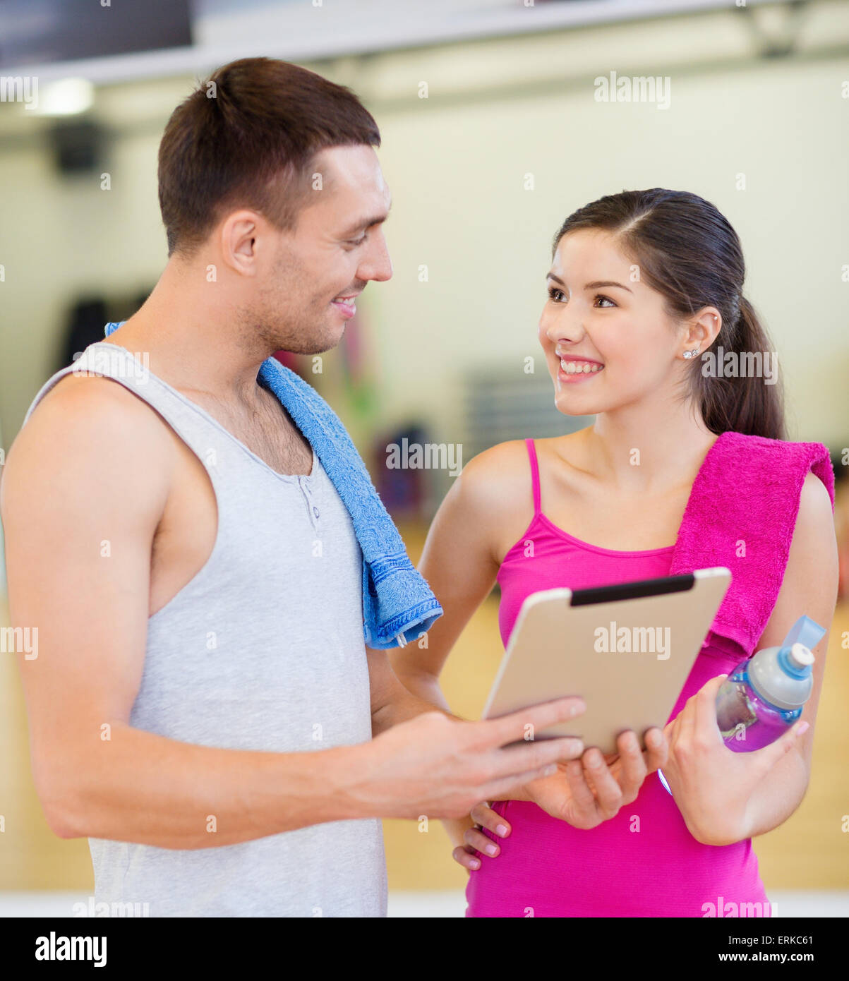 two smiling people with tablet pc in the gym Stock Photo - Alamy
