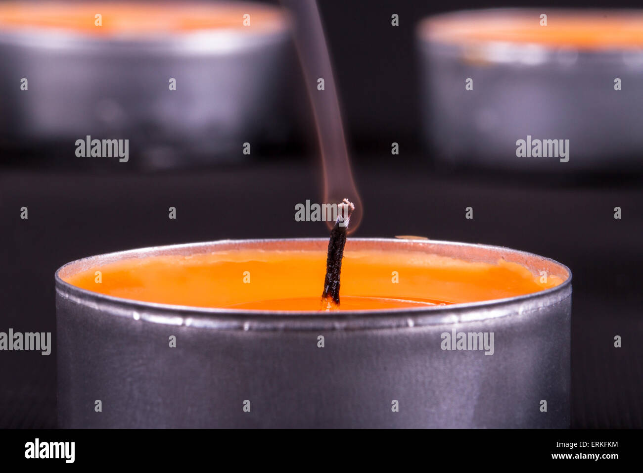 Close up detailed front view of burned out orange candle with smoke, on ...