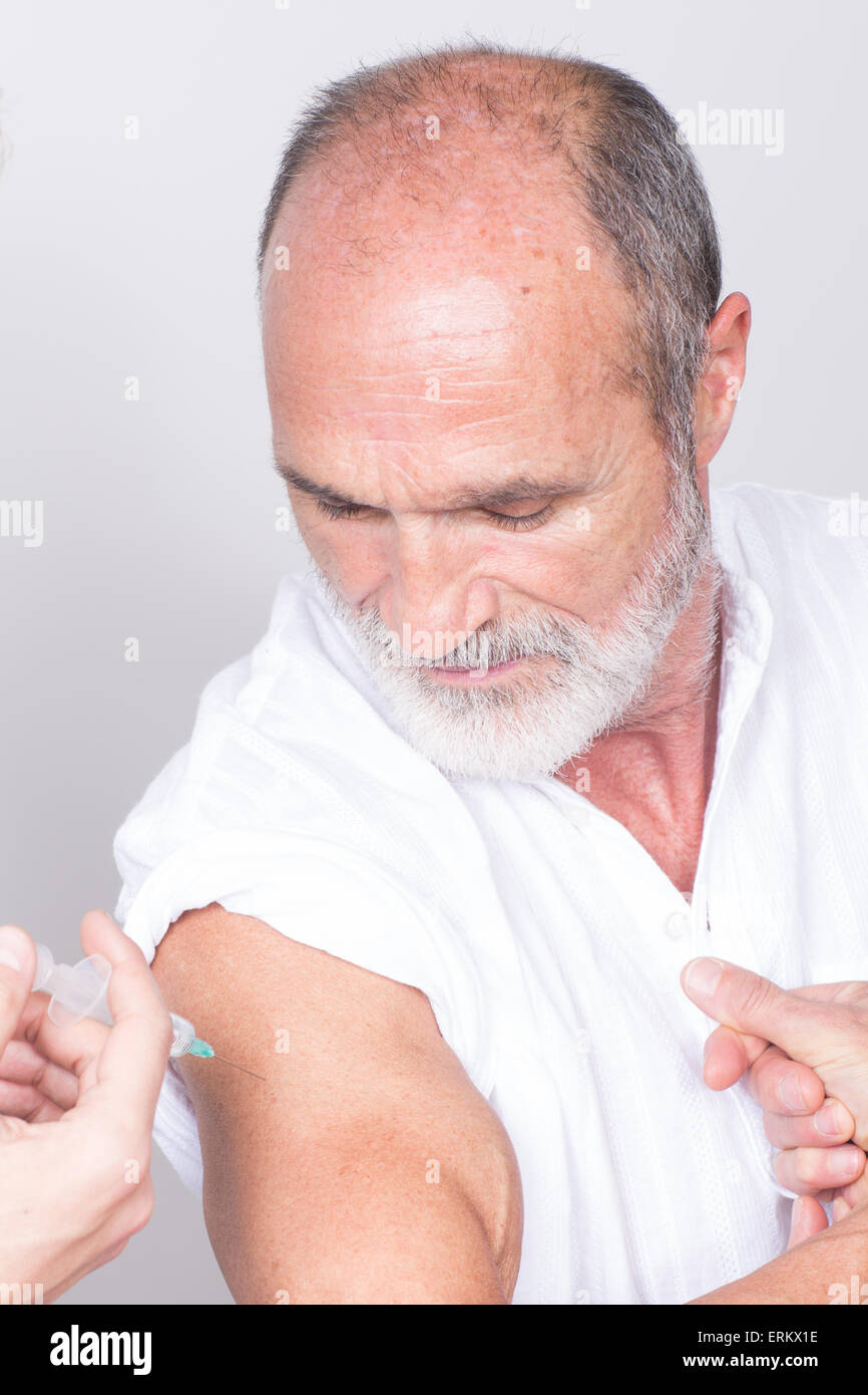 Setting an injection on the arm of an elderly man with grey beard Stock ...