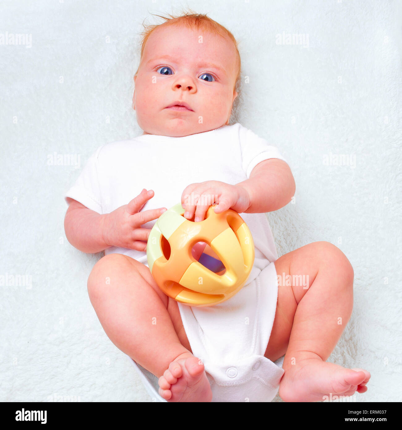 Small laying baby with toy Stock Photo - Alamy
