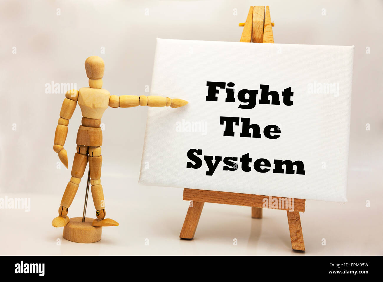 Wooden man with white board pointing at words "fight the system ...