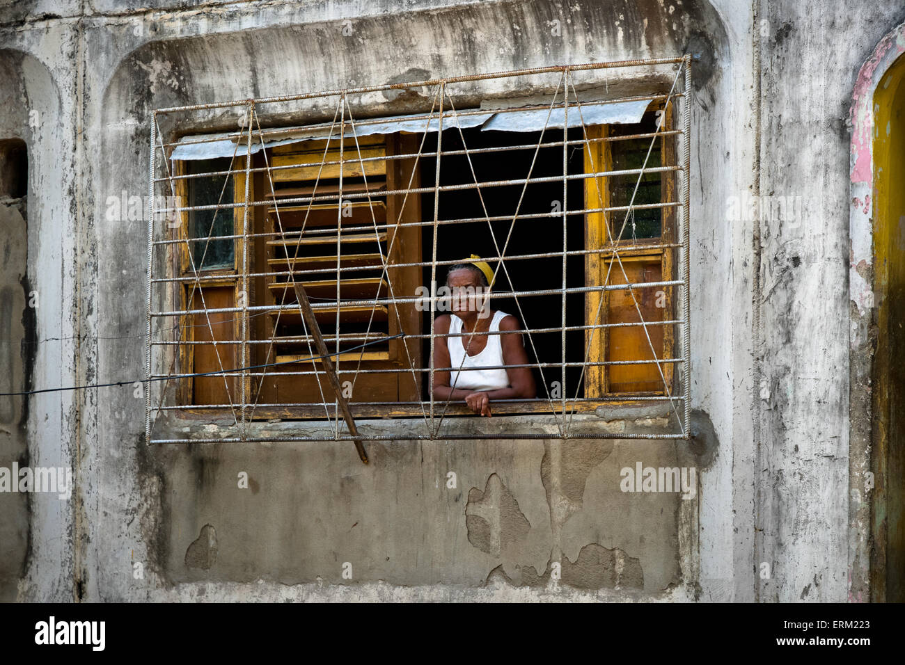 A Cuban woman looks from the barred window in the apartment block in a ...