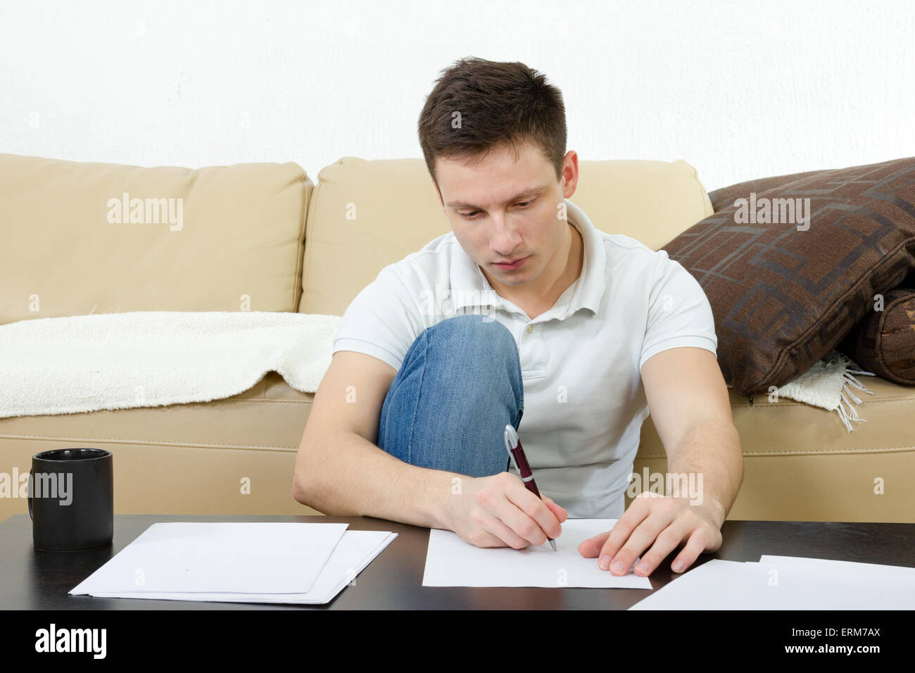 College student concentrating on studying sitting on living room floor ...