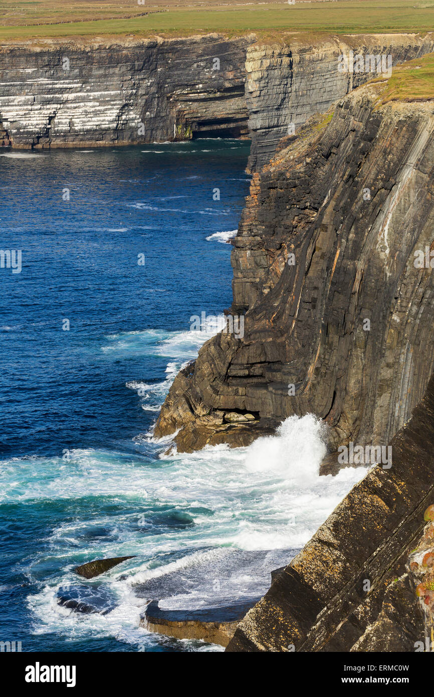 Close up of rugged cliff coastline with waves crashing against the ...