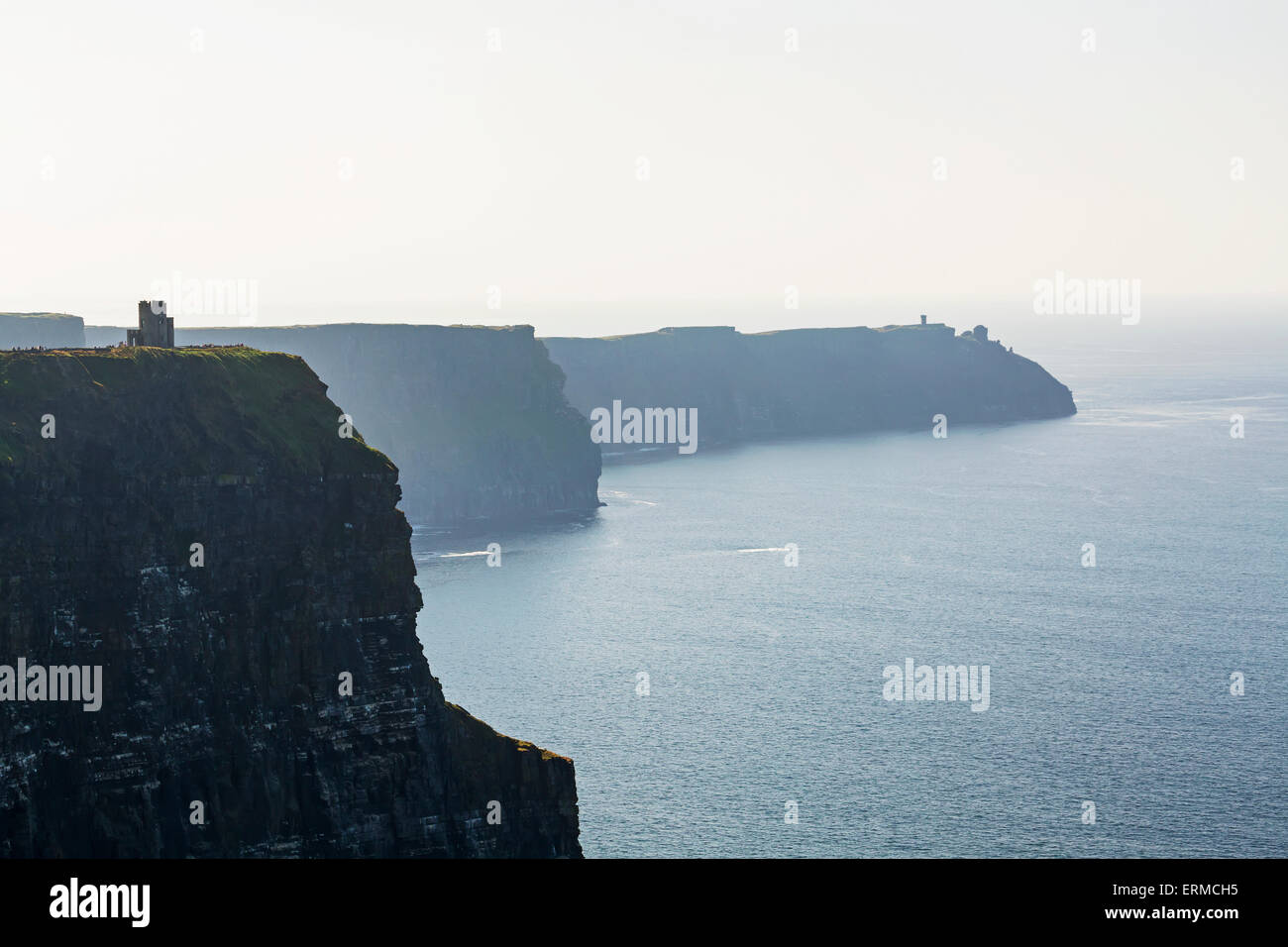 Dramatic rock cliffs along shoreline and castle turret; Liscannor ...