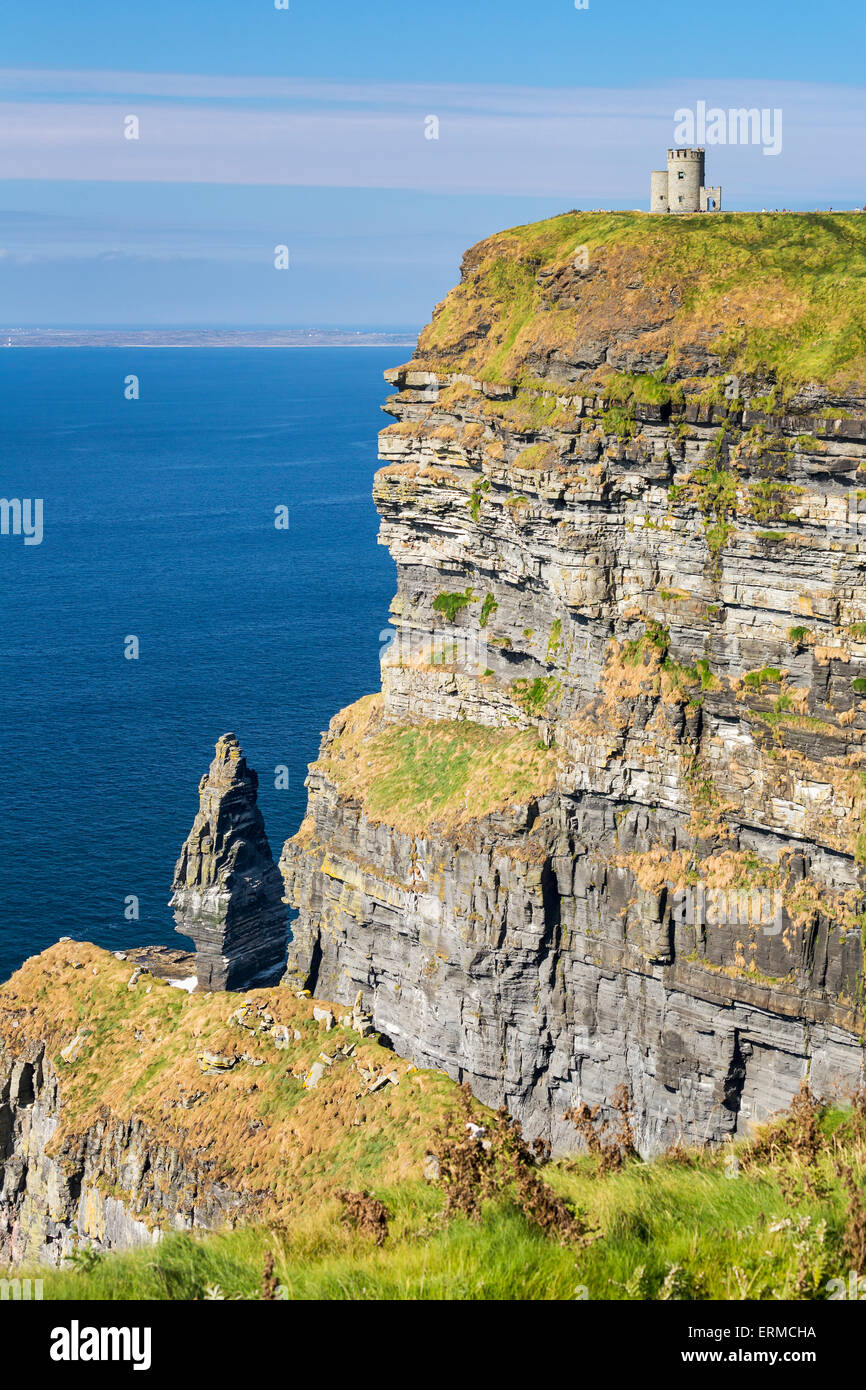 Castle turret on dramatic cliff overlooking the ocean with blue sky ...