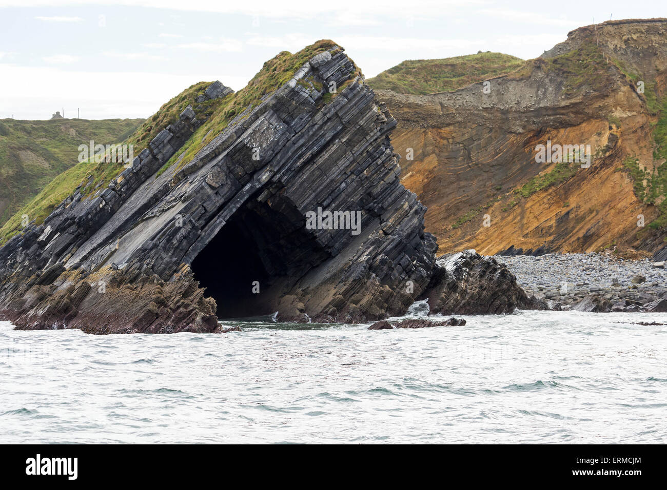 Rock cave eroded out of cliff at water's edge with cliffs in the ...