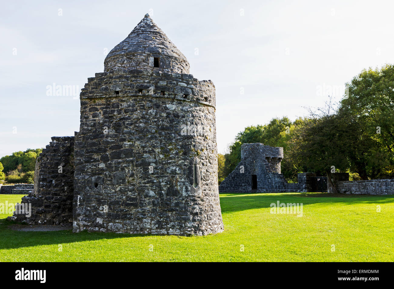 Round stone castle structure in grassy field with stone wall and turret ...