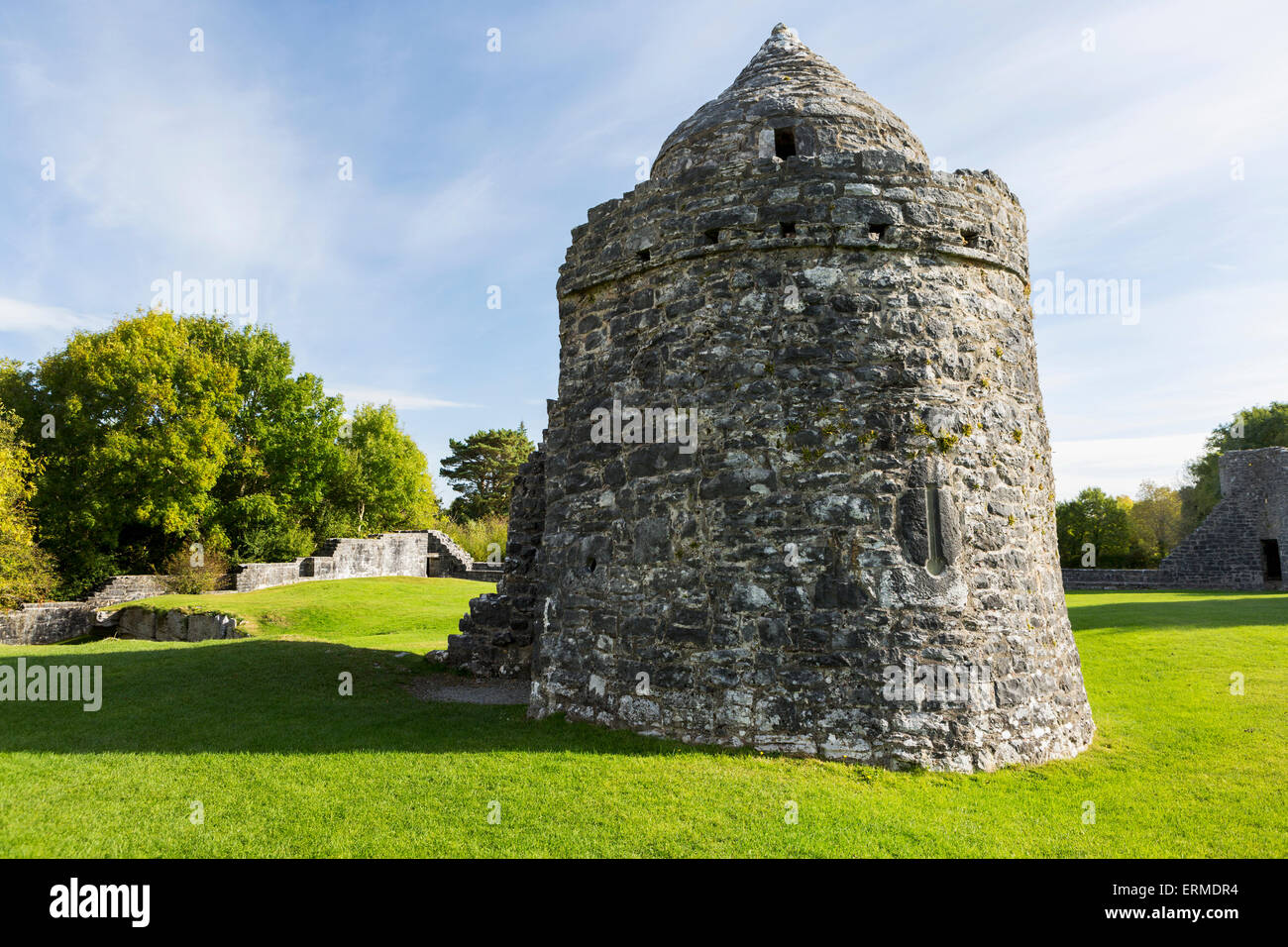 Round stone castle struture in grassy field with blue sky and clouds ...