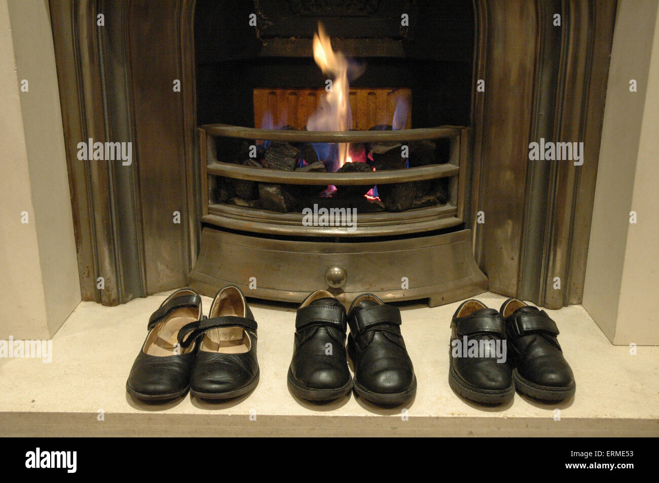 THREE PAIRS OF CHILDREN'S SHOES IN FRONT OF A FIRE Stock Photo - Alamy