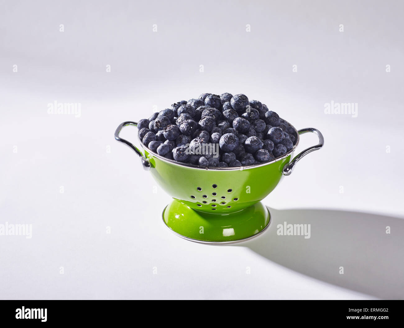 Green colander filled with fresh blueberries Stock Photo - Alamy