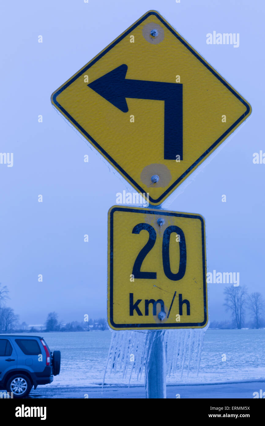 Road sign indicating speed at left turn with icicles hanging from it ...
