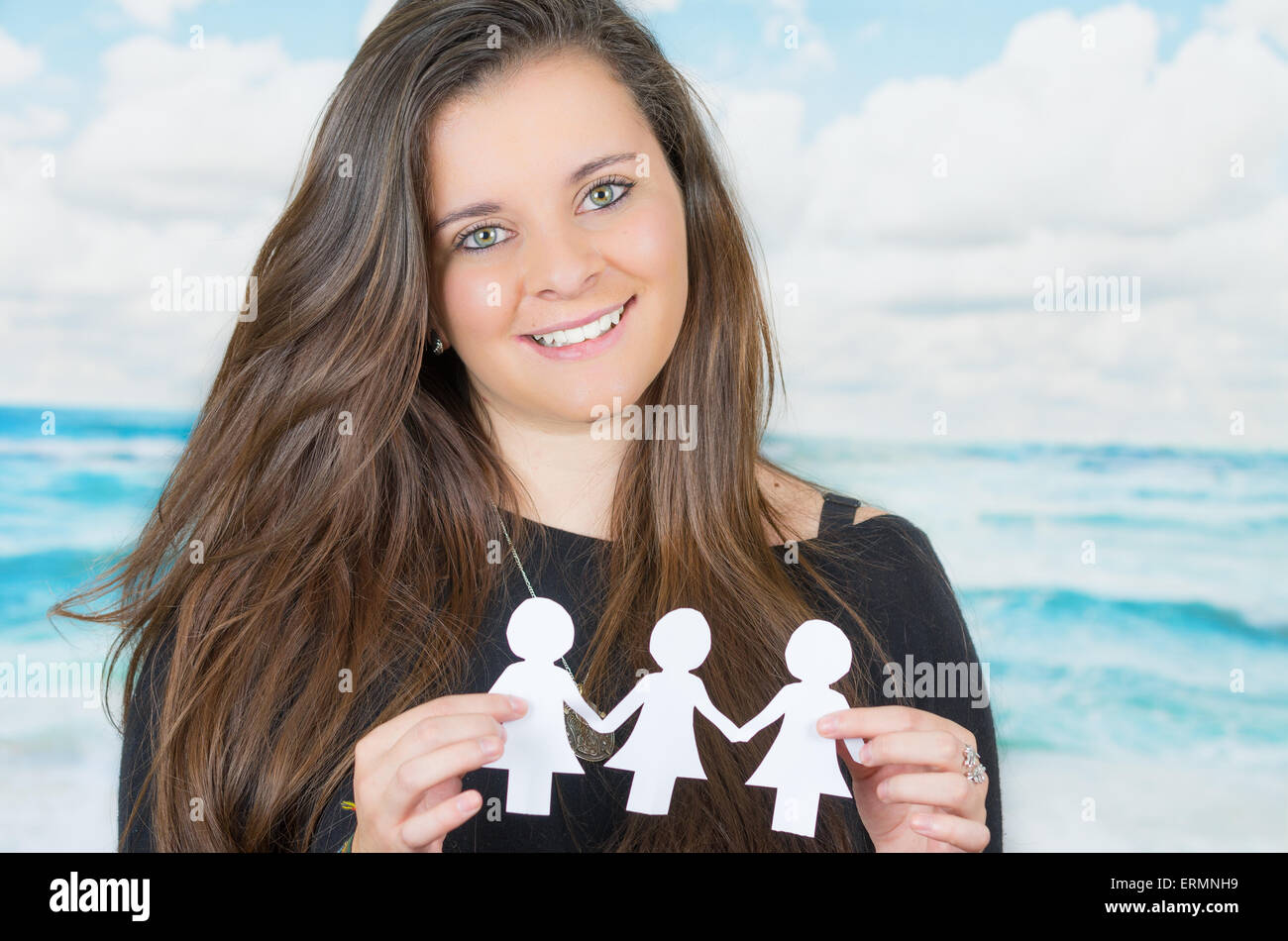 brunette holding an origami paper figure in front of oceanic cloud ...