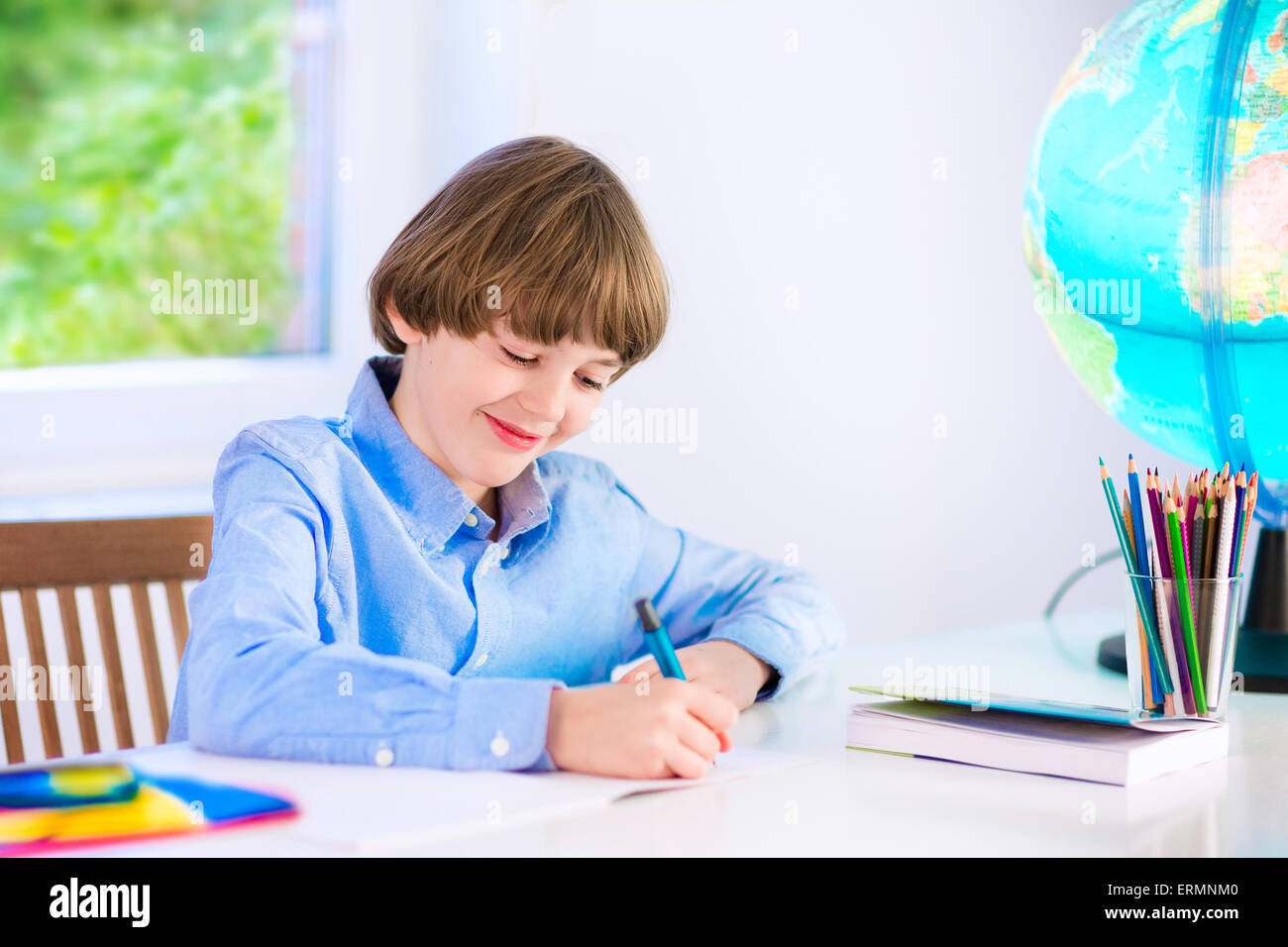 Happy smiling school boy, smart student, doing homework cutting paper ...
