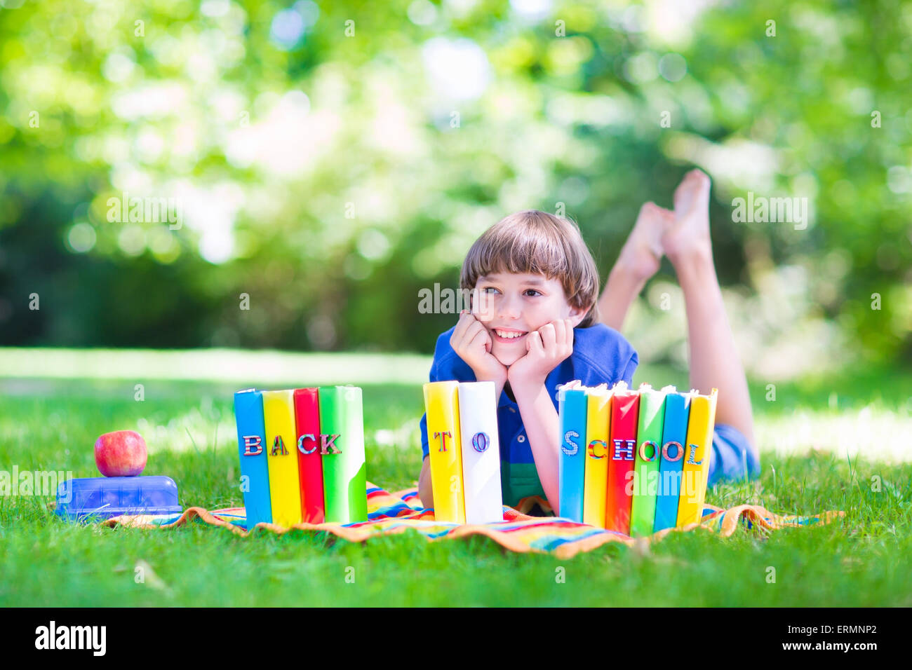 Happy laughing teenager student boy in the school garden reading books ...