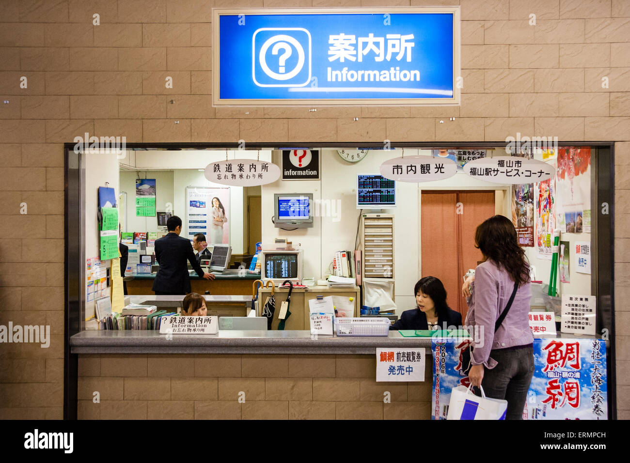 Japanese woman at railway station information desk being served by ...
