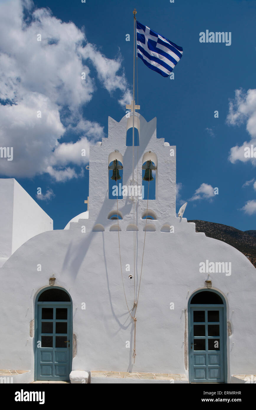 A Greek flag flying over a white washed church; Vathi, Sifnos, Cyclades ...