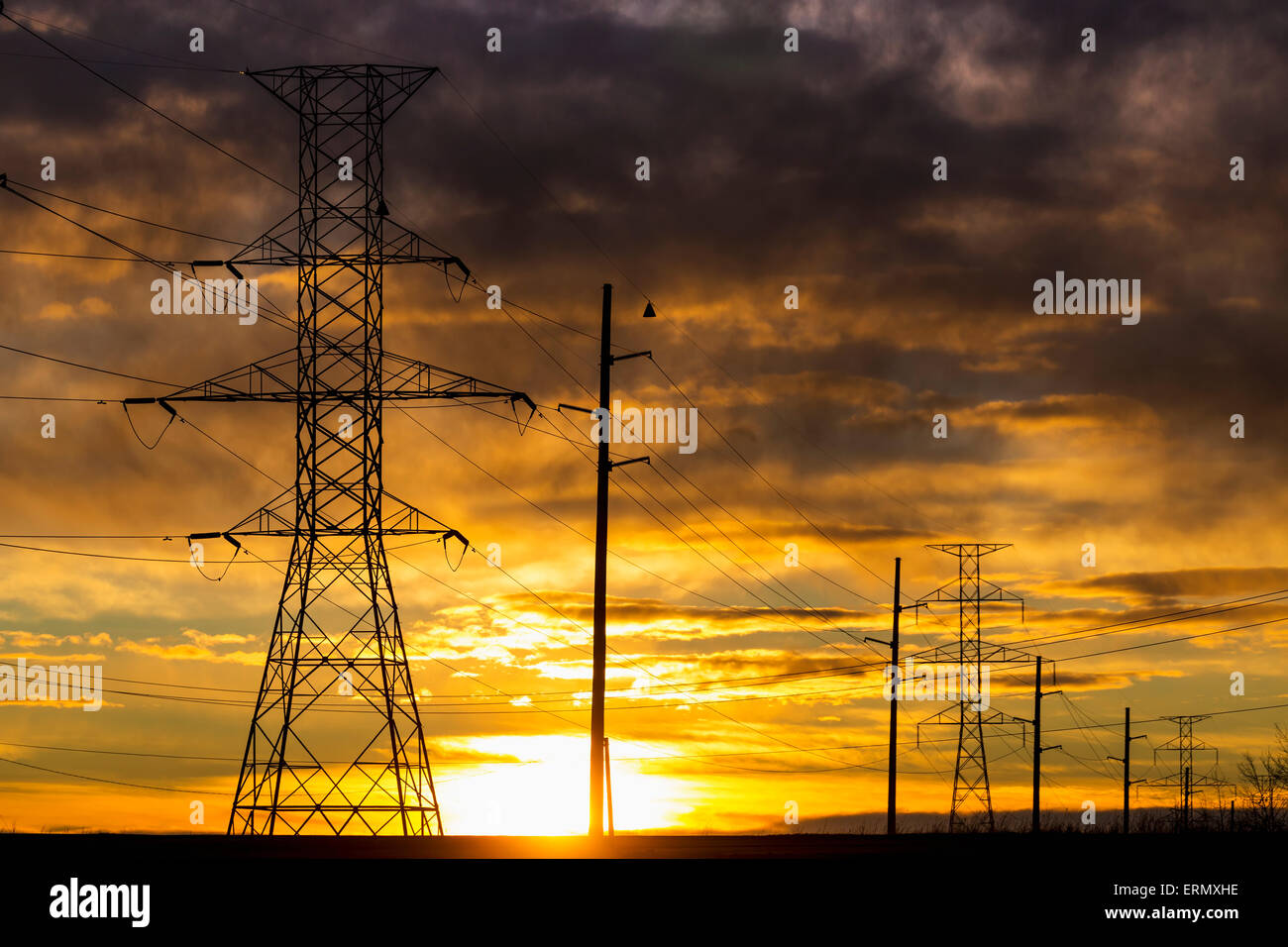 Silhouette of large metal powerline towers with colourful clouds and ...