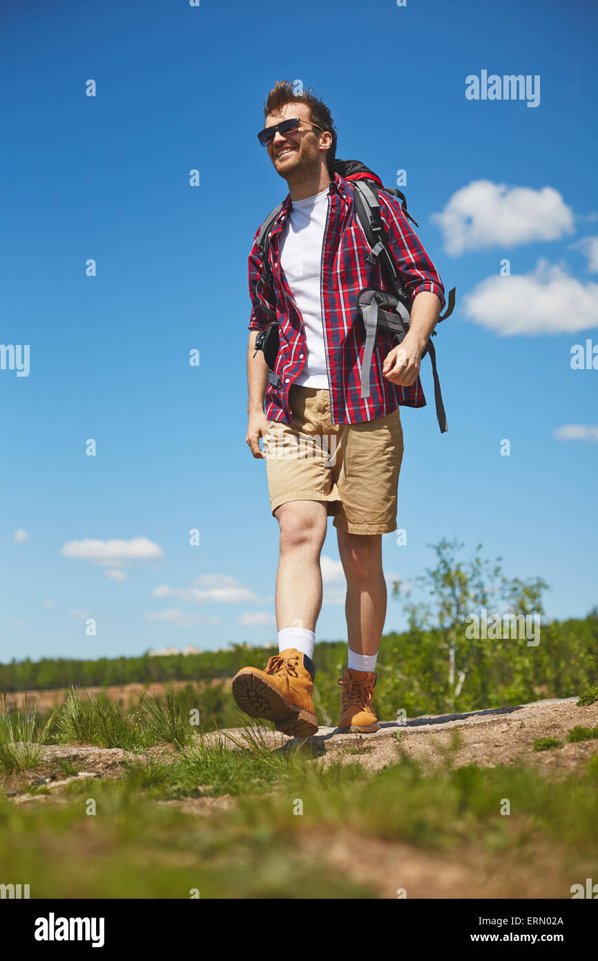 Handsome tourist with backpack going in countryside Stock Photo - Alamy