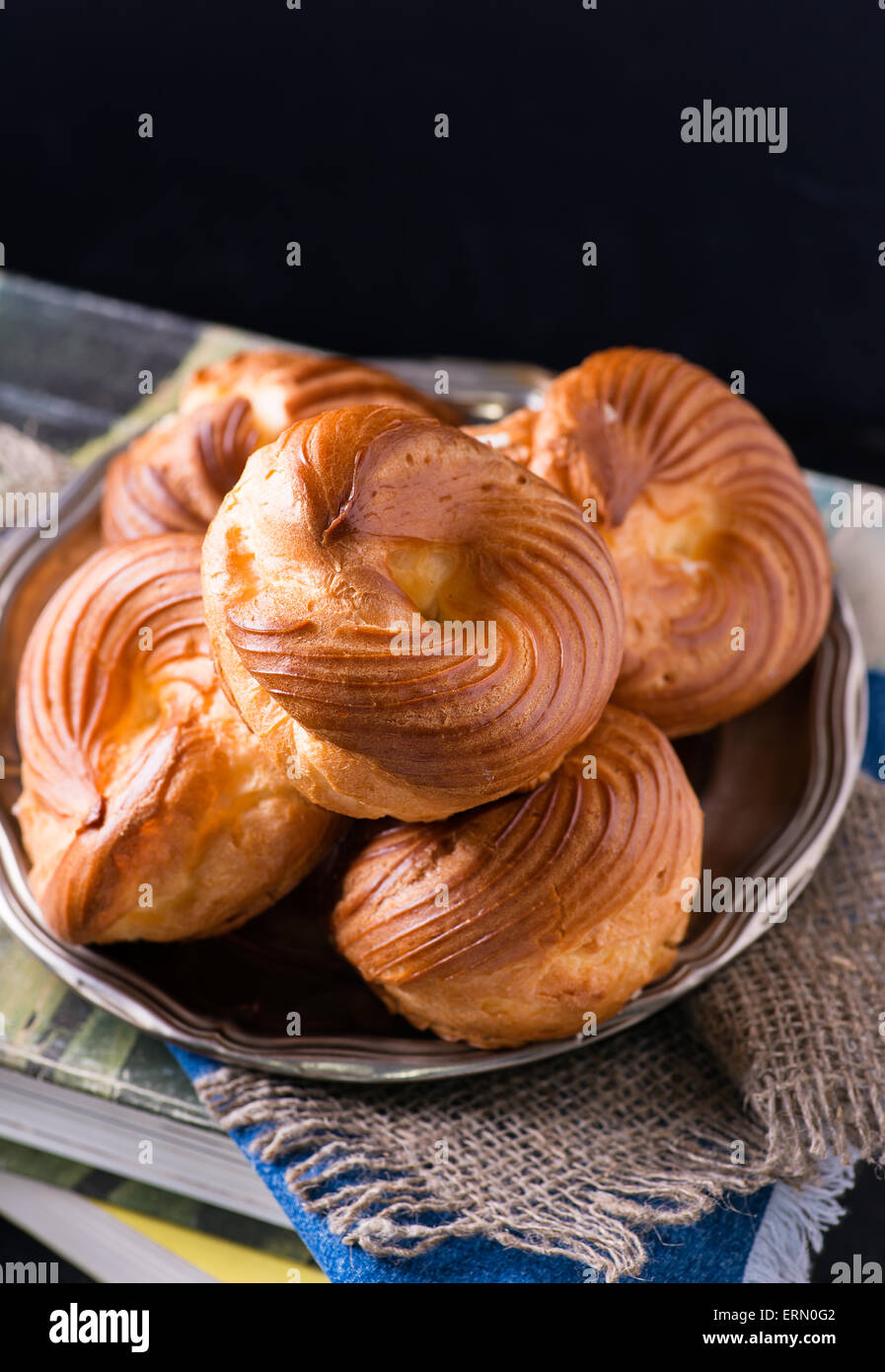 Choux pastry eclair ring with custard cream on dark background ...