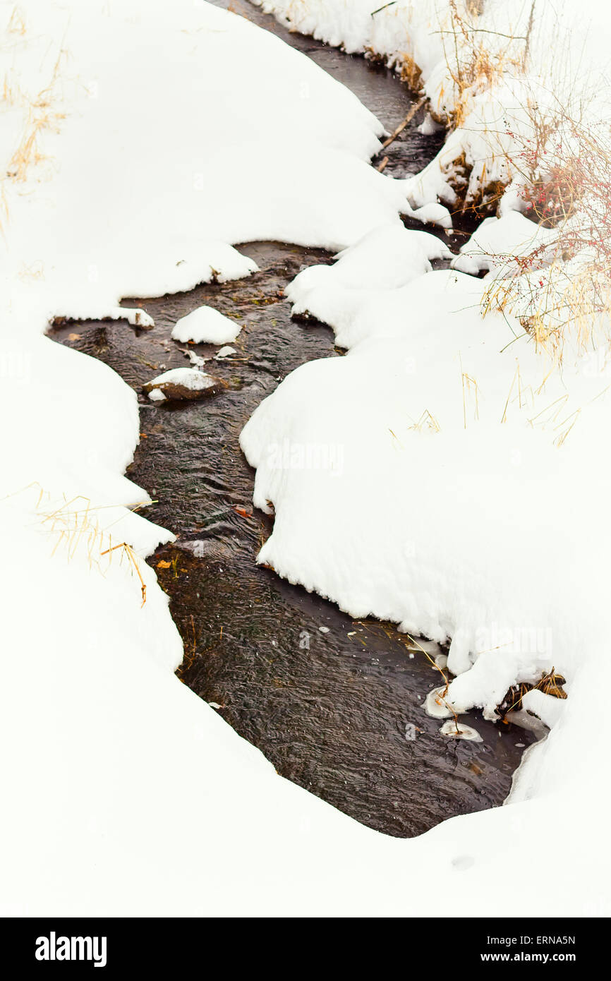 Stream slowly trickles through the ice and snow of winter Stock Photo ...