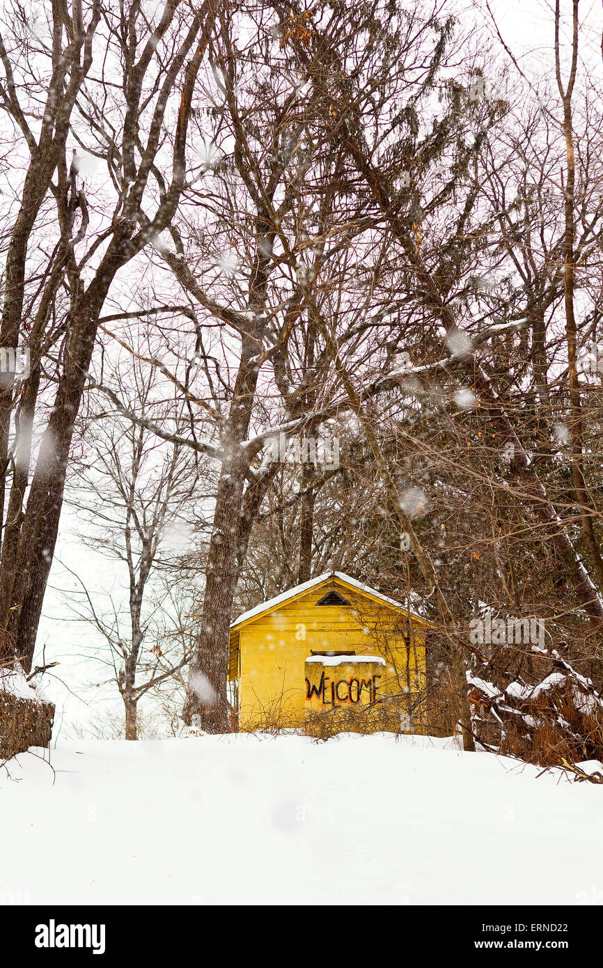Welcome graffiti on yellow abandoned outhouse on a snowy day with ...