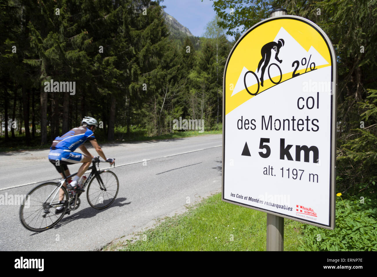 A cyclist rides past a sign for the Col des Montets, Haute-Savoie ...