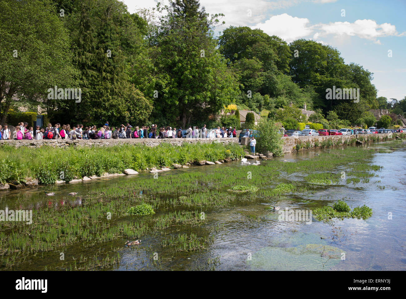 French school children walking along the River Coln in Bibury ...