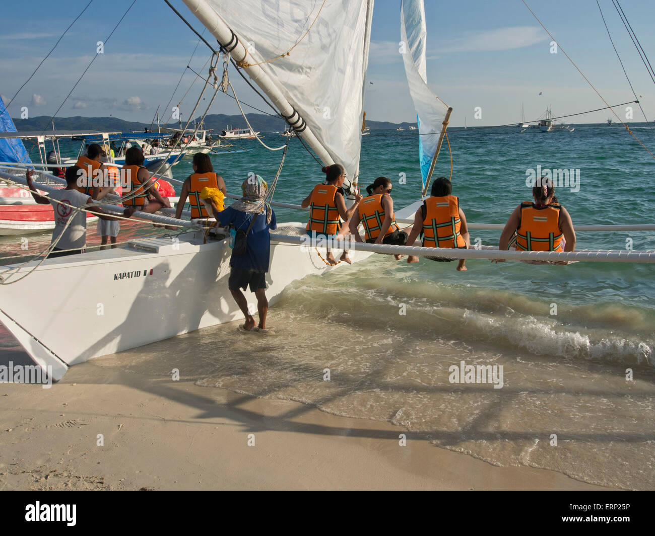 Tourists boarding a traditional panga boat in Boracay, Philippines ...
