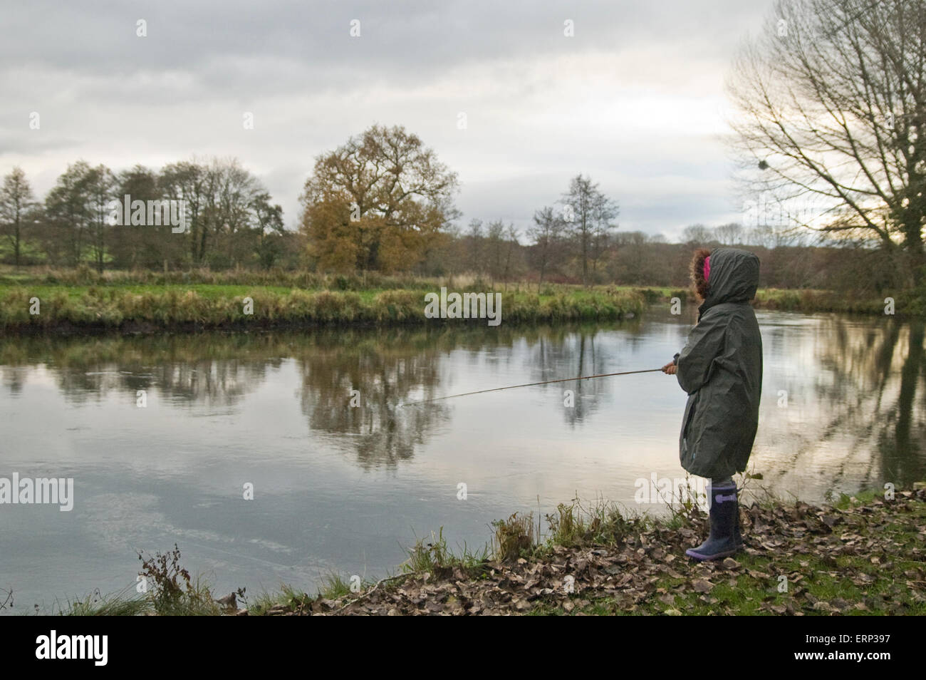 A young fisher girl tries to catch a fish on an english chalkstream ...